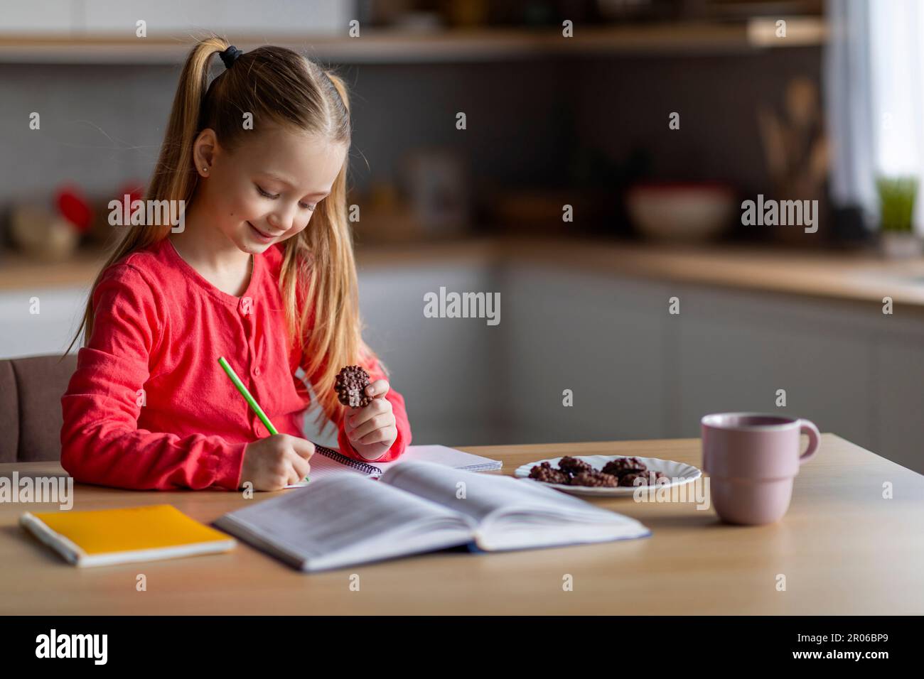 Cute Little Girl Doing School Homework And Eating Cookies At Home Stock ...