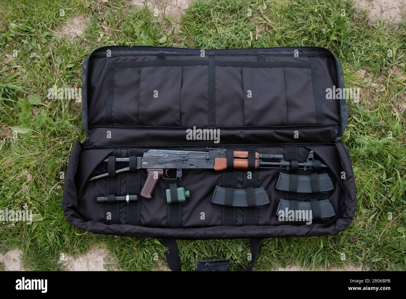 Uncovered gun case with AK-47, magazines, and flashlight lying on the ...