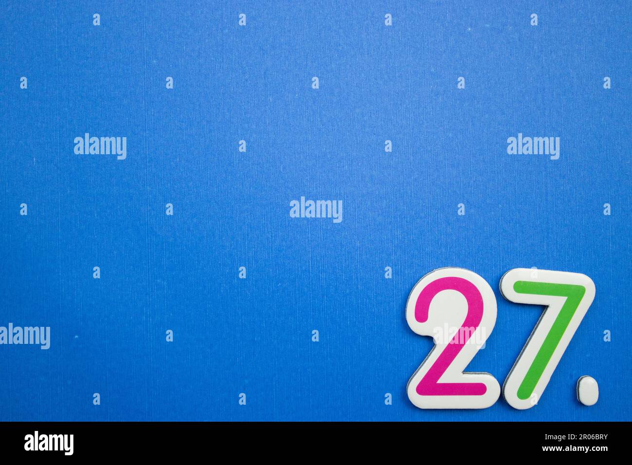 The number 27, placed on the edge of a blue background, photographed ...