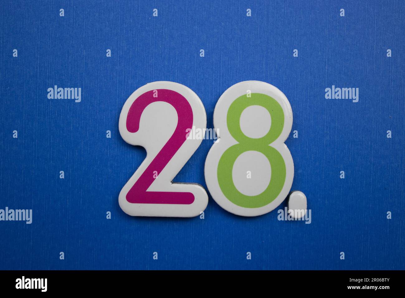 The number 28, placed on a blue background, photographed from above ...