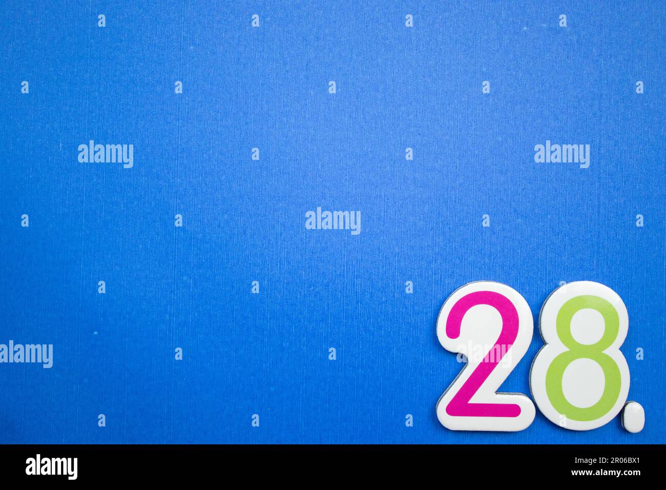 The number 28, placed on the edge of a blue background, photographed ...