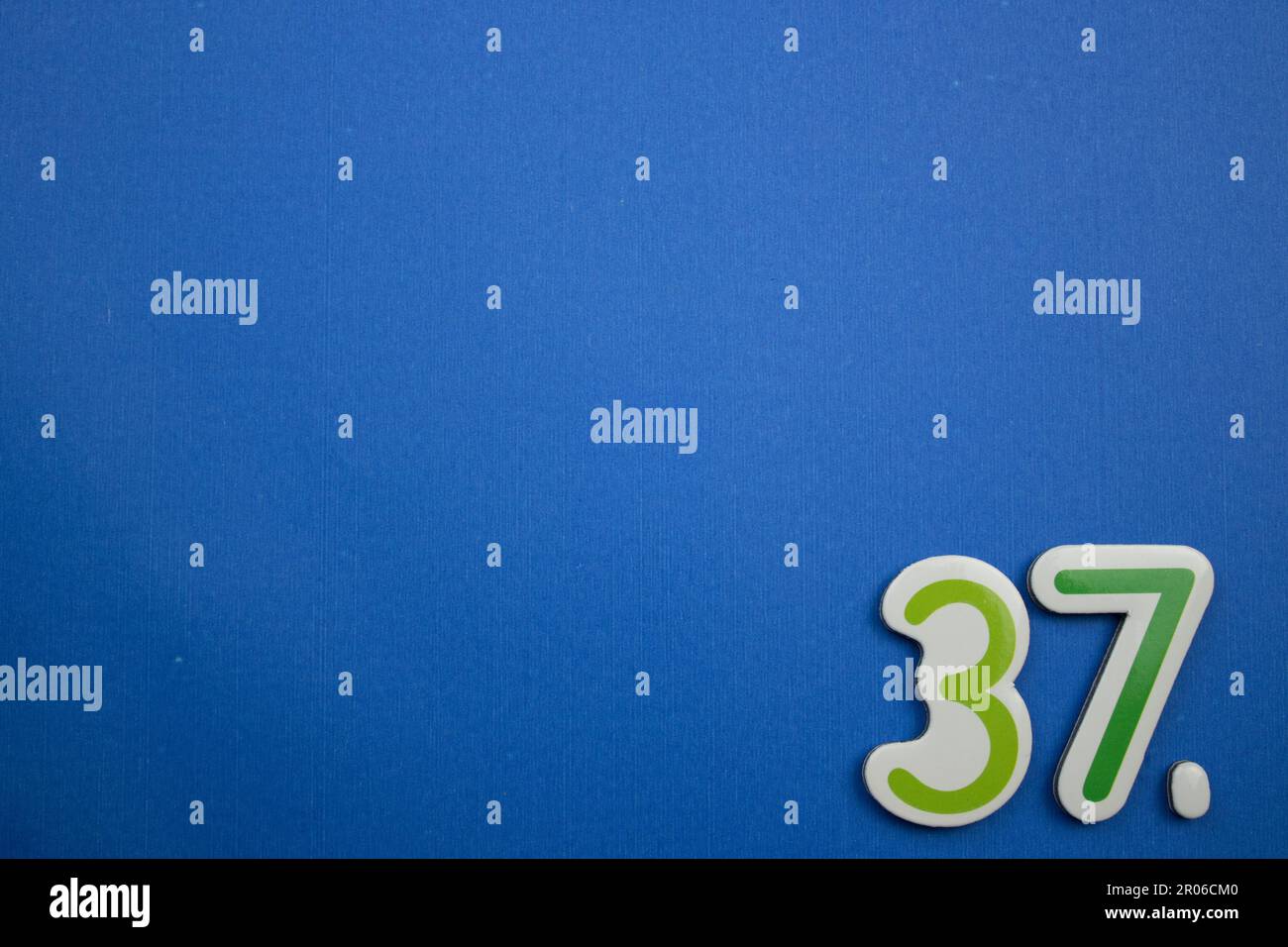 The number 37, placed on the edge of a blue background, photographed ...