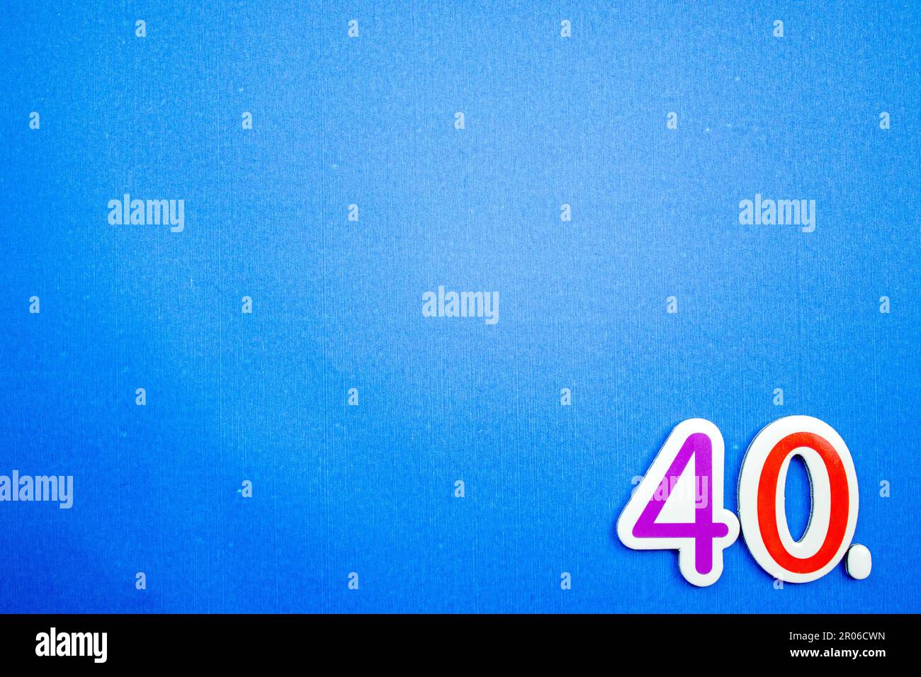 The number 40, placed on the edge of a blue background, photographed from above, colored purple ...