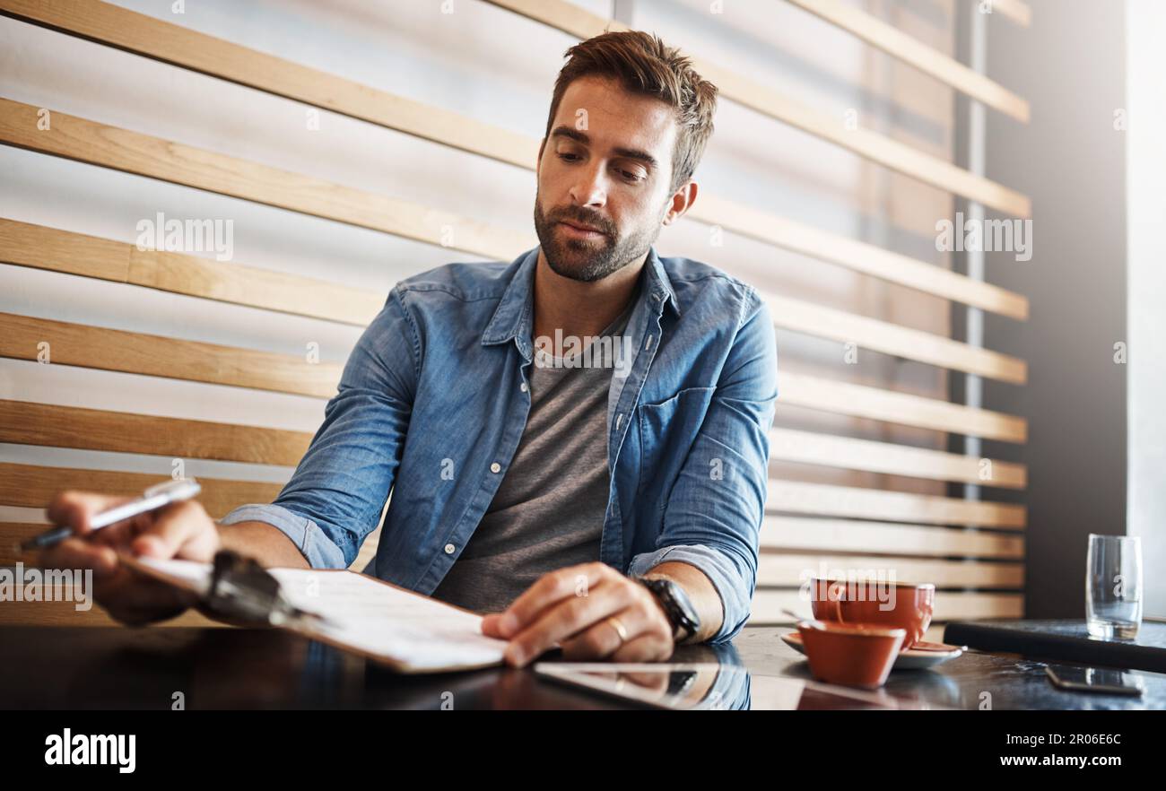 Month end at the coffee shop. a handsome young man working in a coffee ...