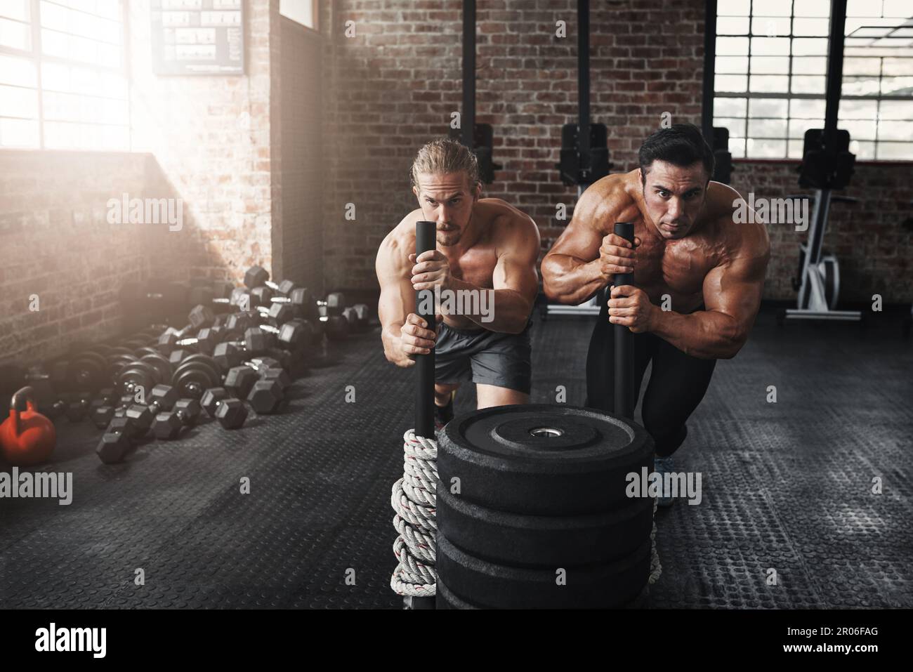 Work those muscles like never before. two muscular young men pushing a ...