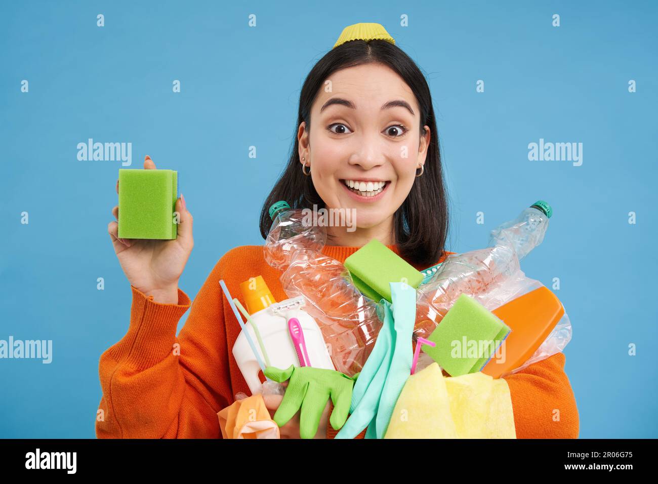 Smiling enthusiastic female eco activist, holding cleaning sponge ...