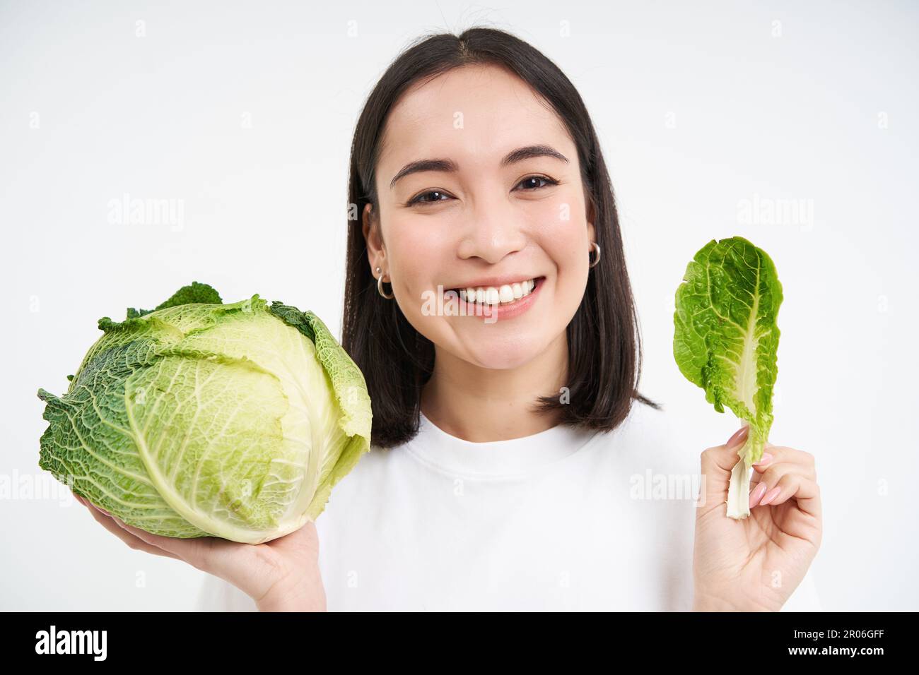 Close up portrait of asian woman, biting lettuce, eating green cabbage ...