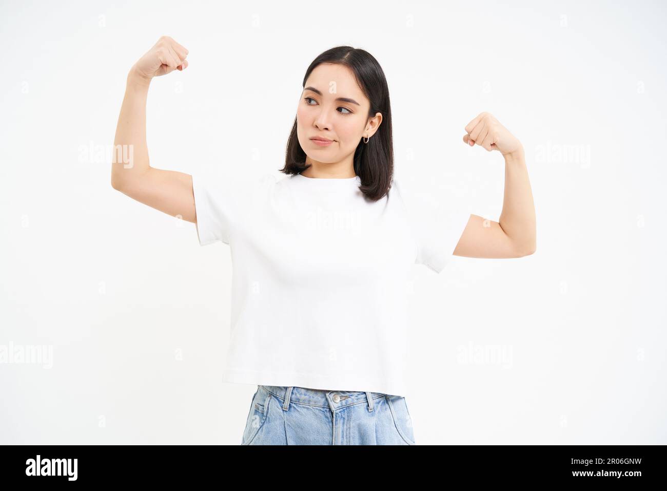 Smiling asian woman, flexing biceps, looking sassy and strong, showing ...