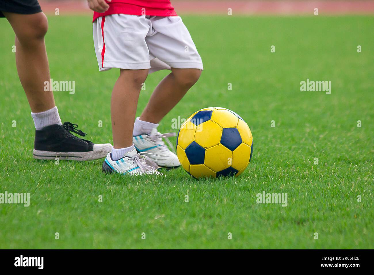 Legs of kids are kicking football Stock Photo - Alamy