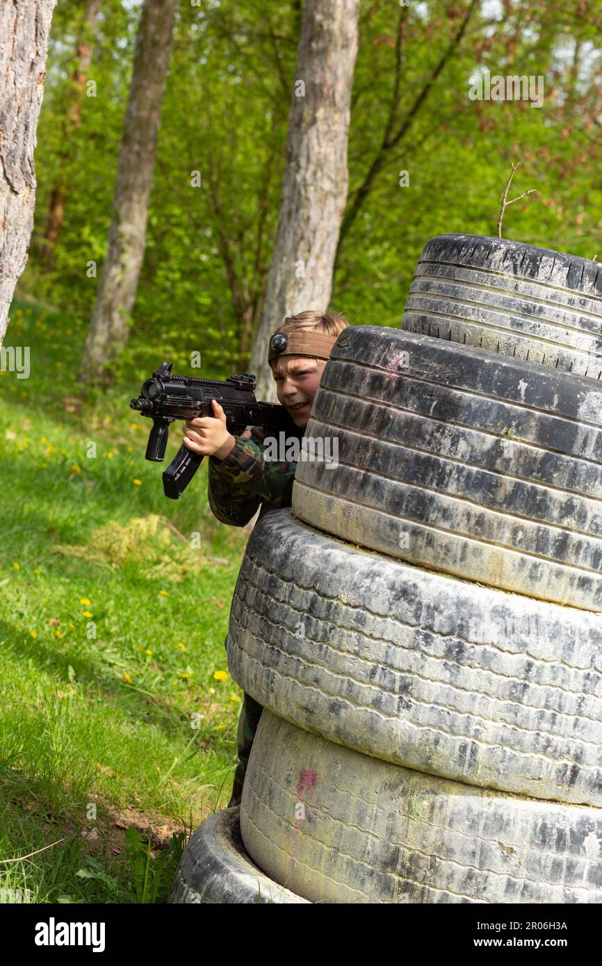 Boy weared in camouflage playing laser tag in special forest playground ...