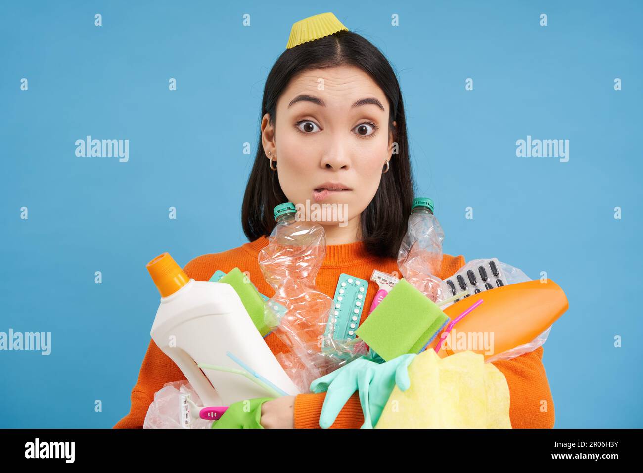 Portrait of asian woman with intrigued face, holds rubbish for ...