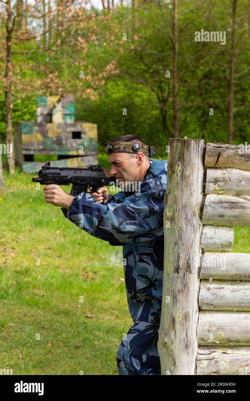 Young man weared in camouflage playing laser tag in special forest ...