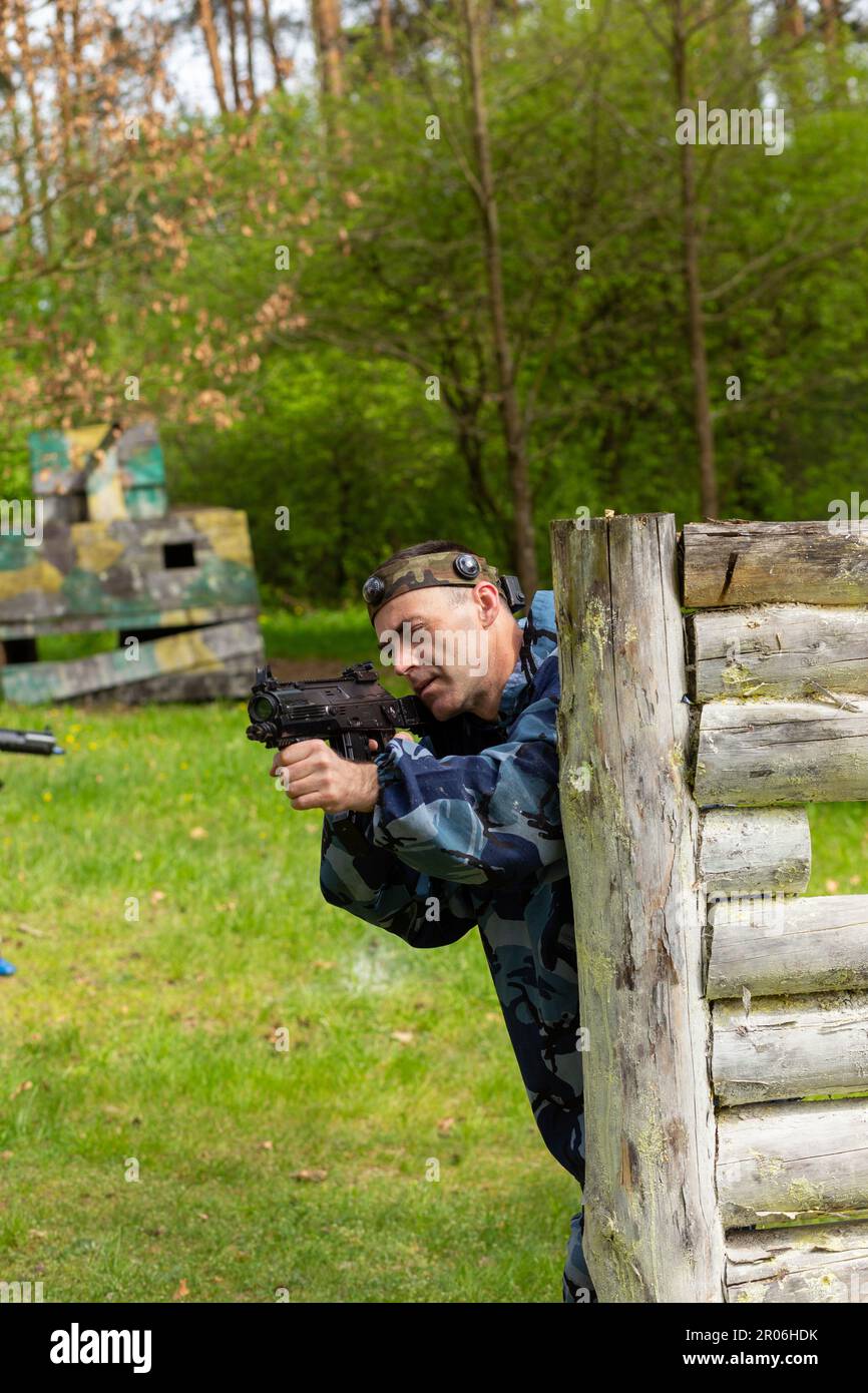 Young man weared in camouflage playing laser tag in special forest ...