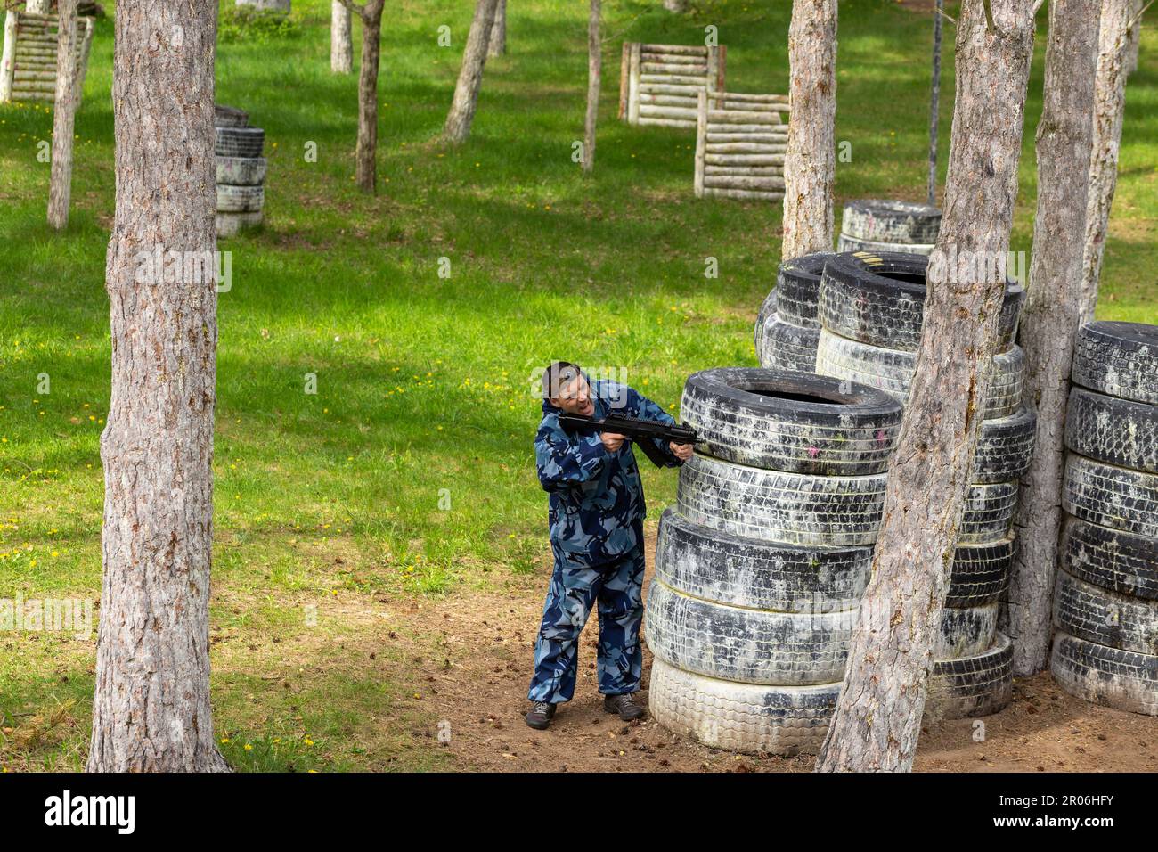 Young man weared in camouflage playing laser tag in special forest ...