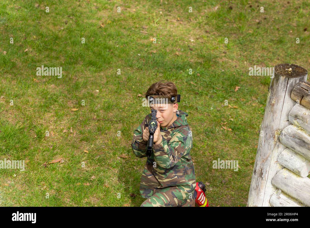 Boy weared in camouflage playing laser tag in special forest playground ...
