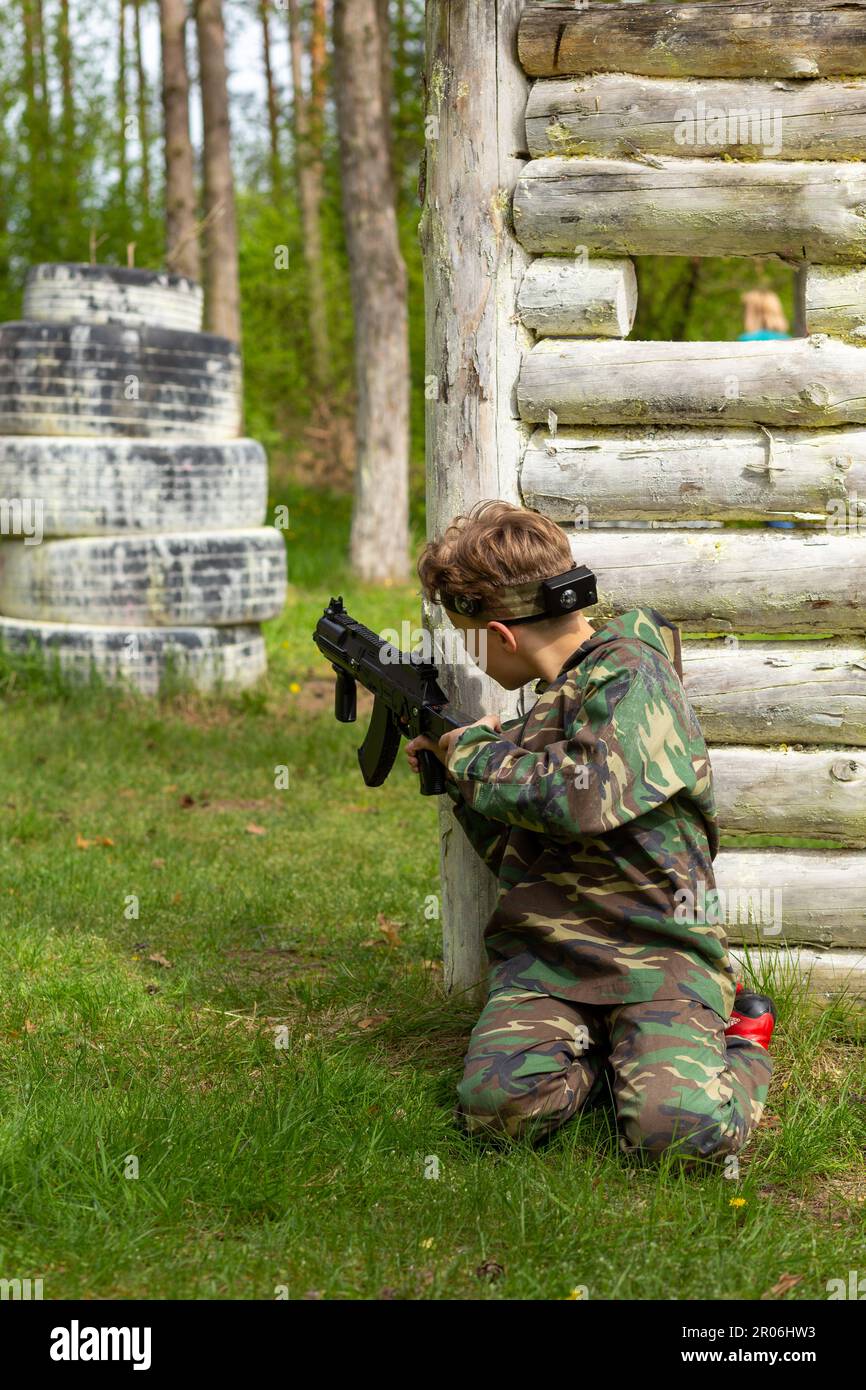 Boy weared in camouflage playing laser tag in special forest playground ...