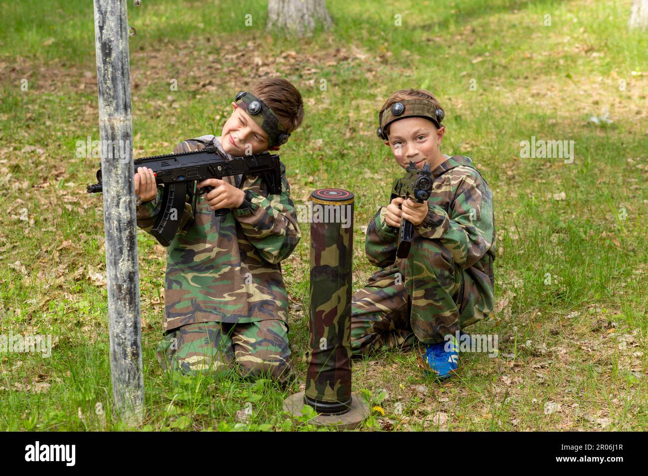 Two boys weared in camouflage playing laser tag in special forest ...