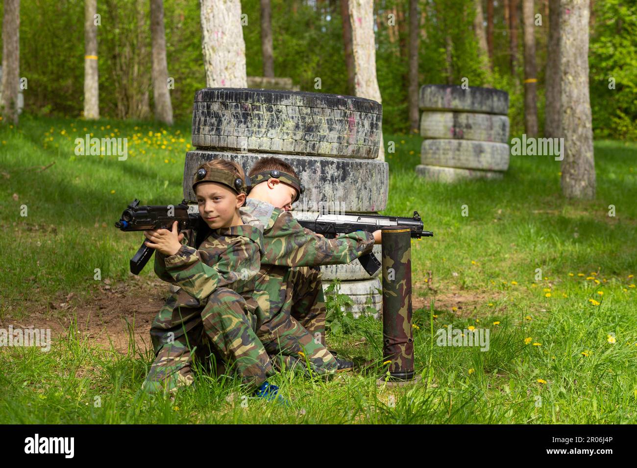 Two boys weared in camouflage playing laser tag in special forest ...