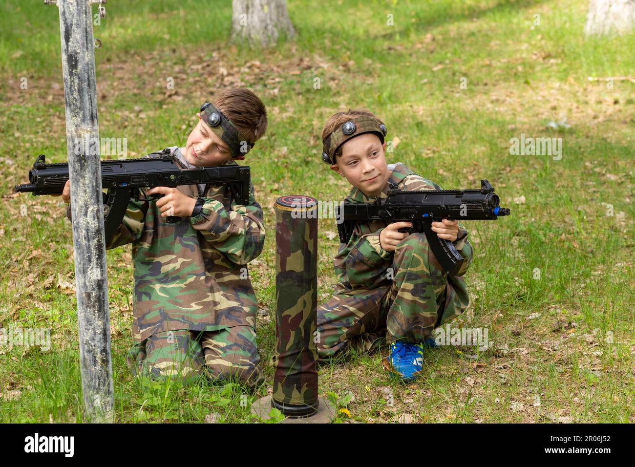 Two boys weared in camouflage playing laser tag in special forest ...