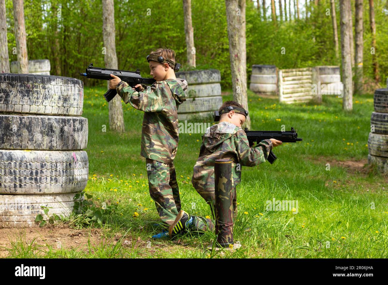 Two boys weared in camouflage playing laser tag in special forest ...