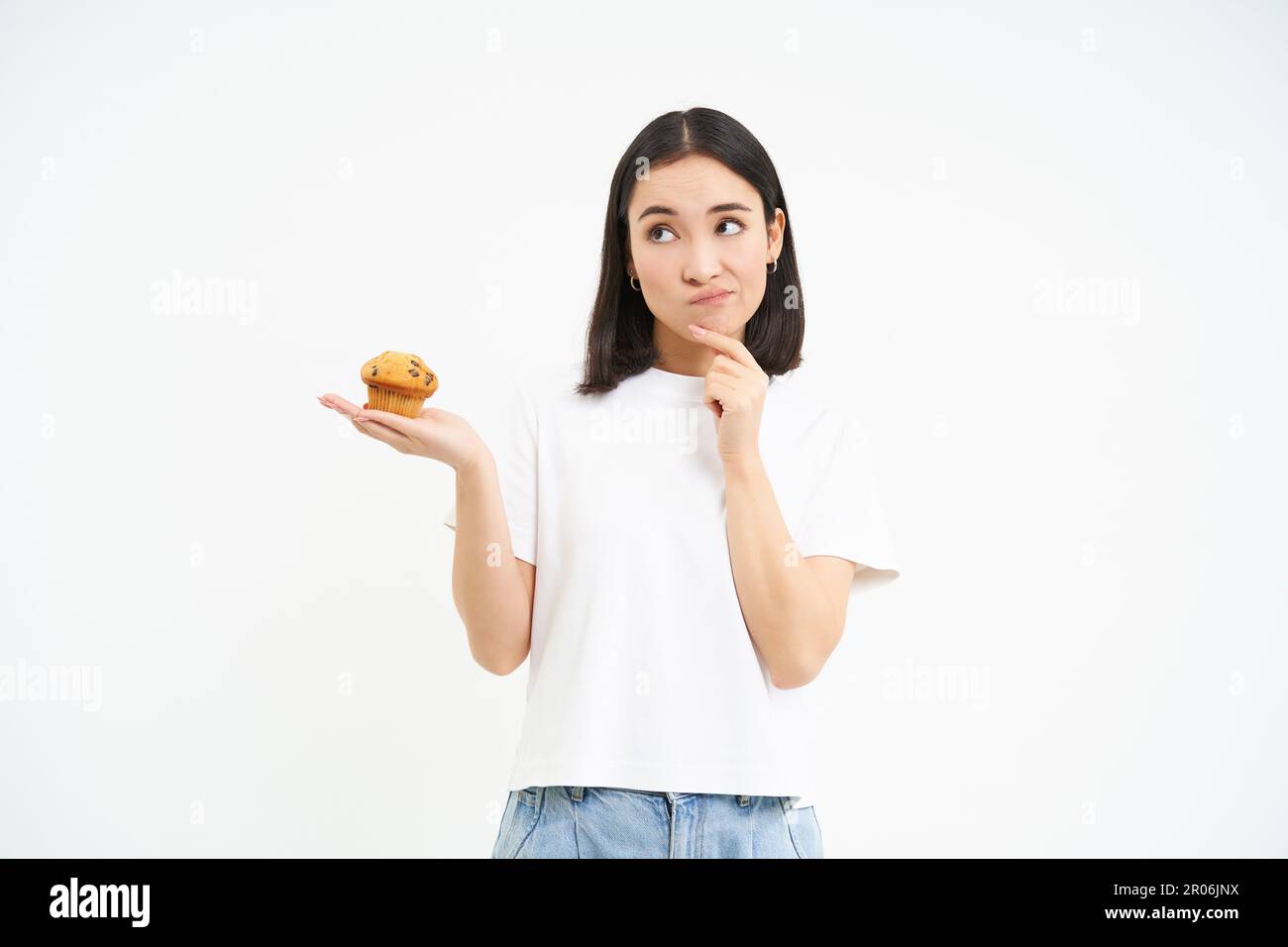 Woman with pensive face, holding cupcake and thinking, white background ...