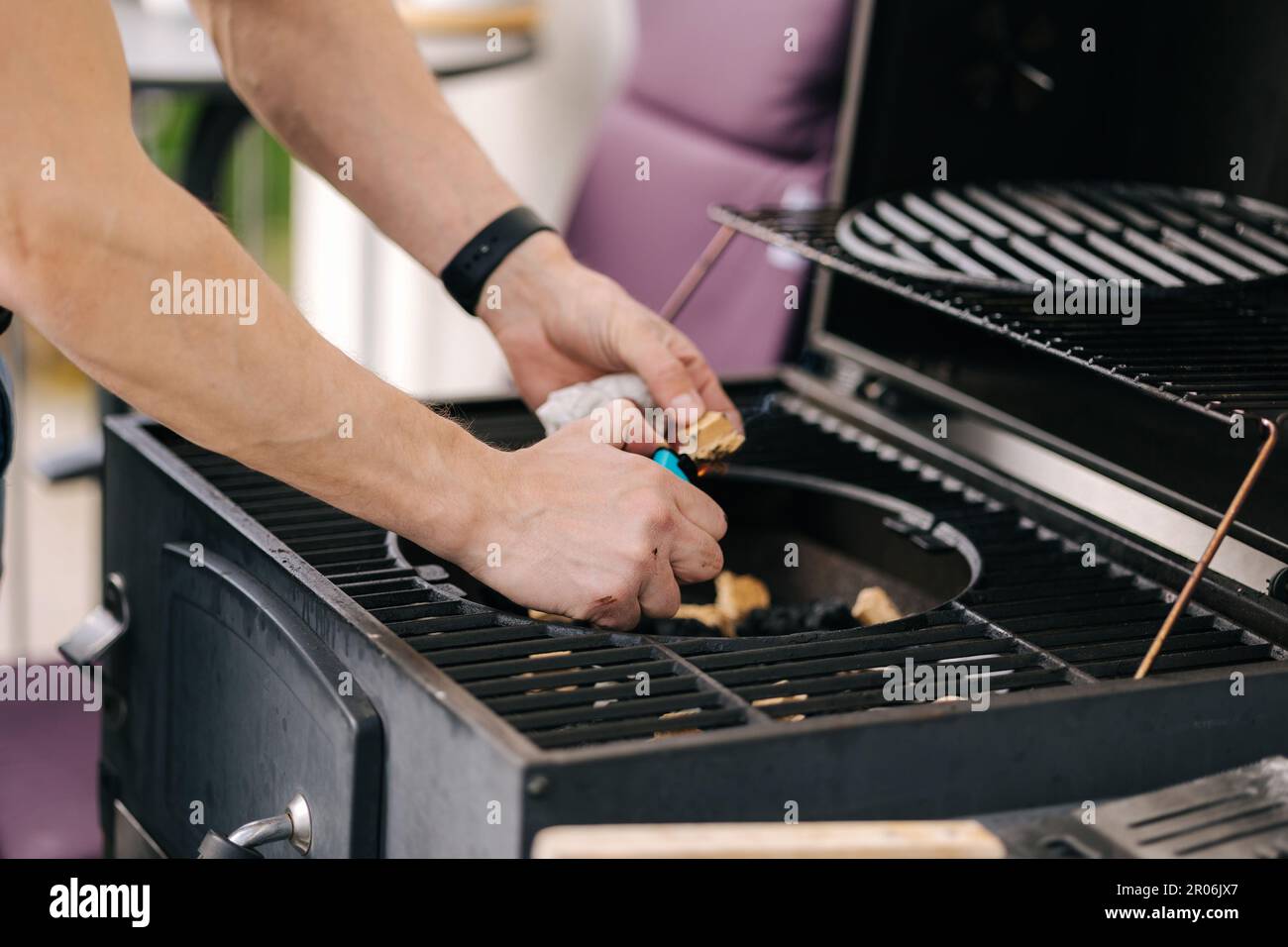 Close-up of human hand hold lighter and lights a fire in BBQ grill on ...