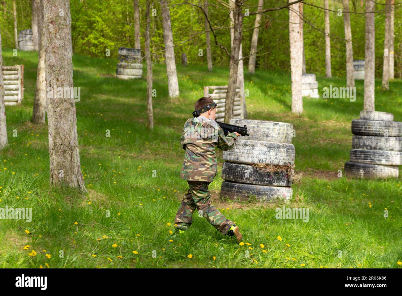 Boy weared in camouflage playing laser tag in special forest playground ...