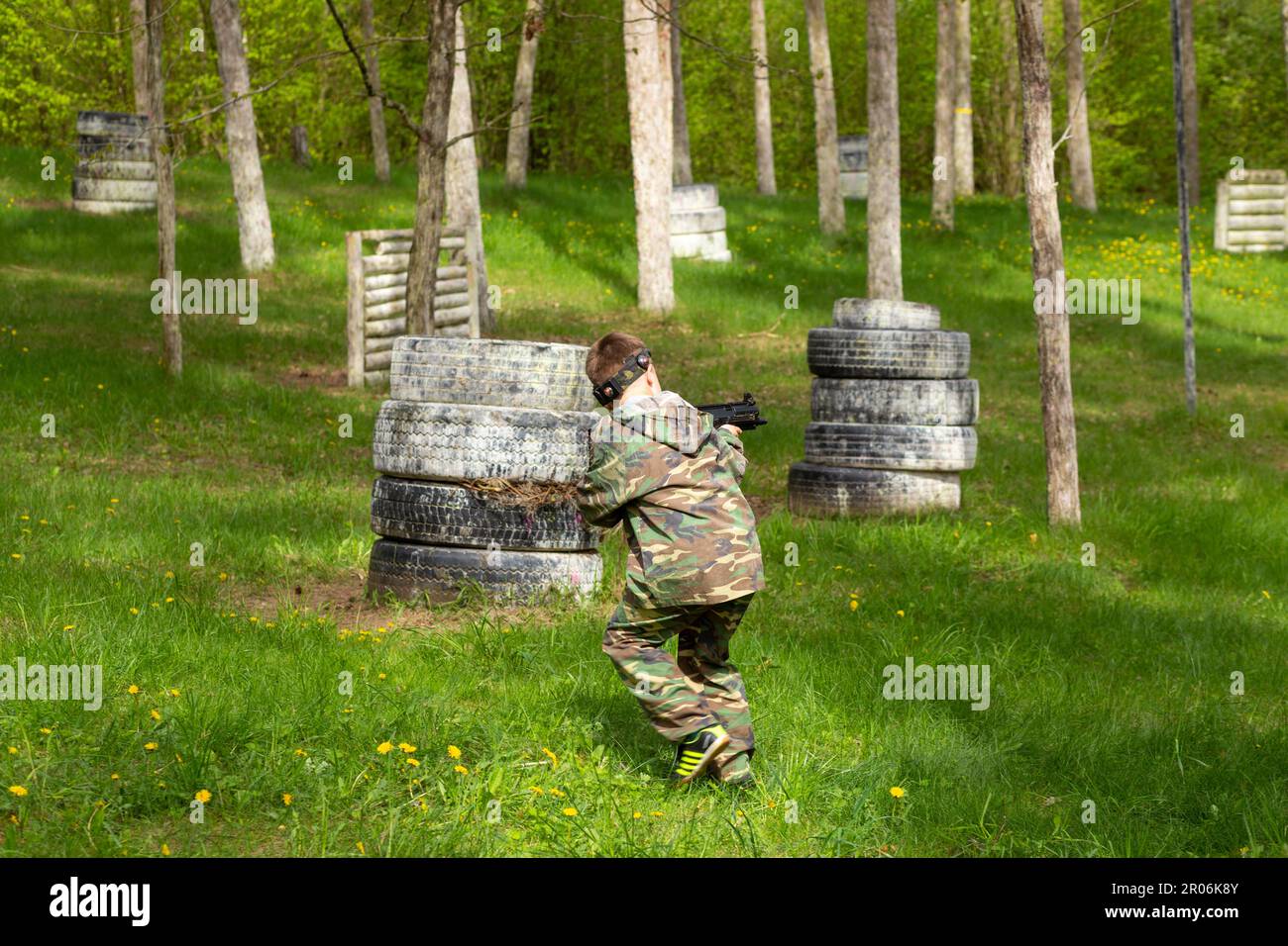 Boy weared in camouflage playing laser tag in special forest playground ...