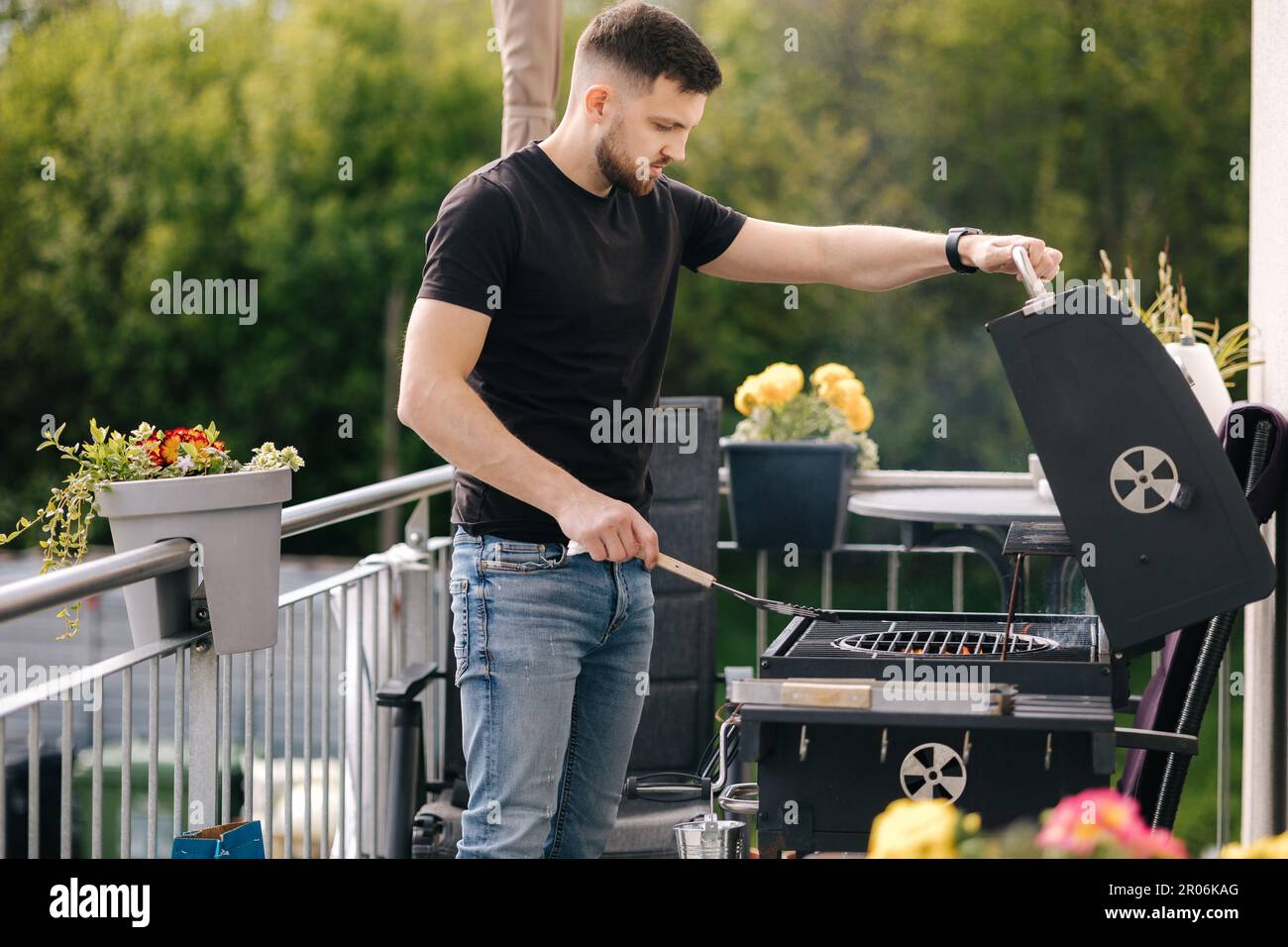 Side view of man open BBQ to see how the fire burns. Preparing for ...