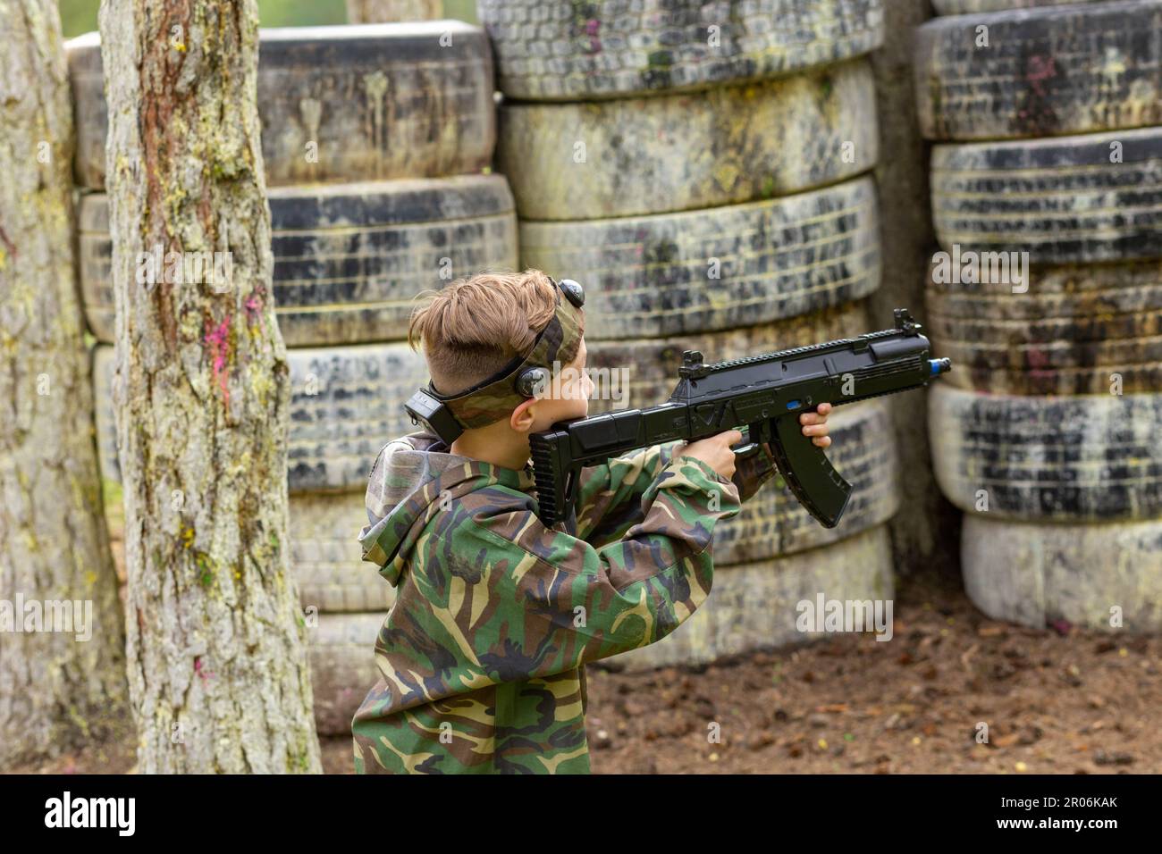 Boy weared in camouflage playing laser tag in special forest playground ...
