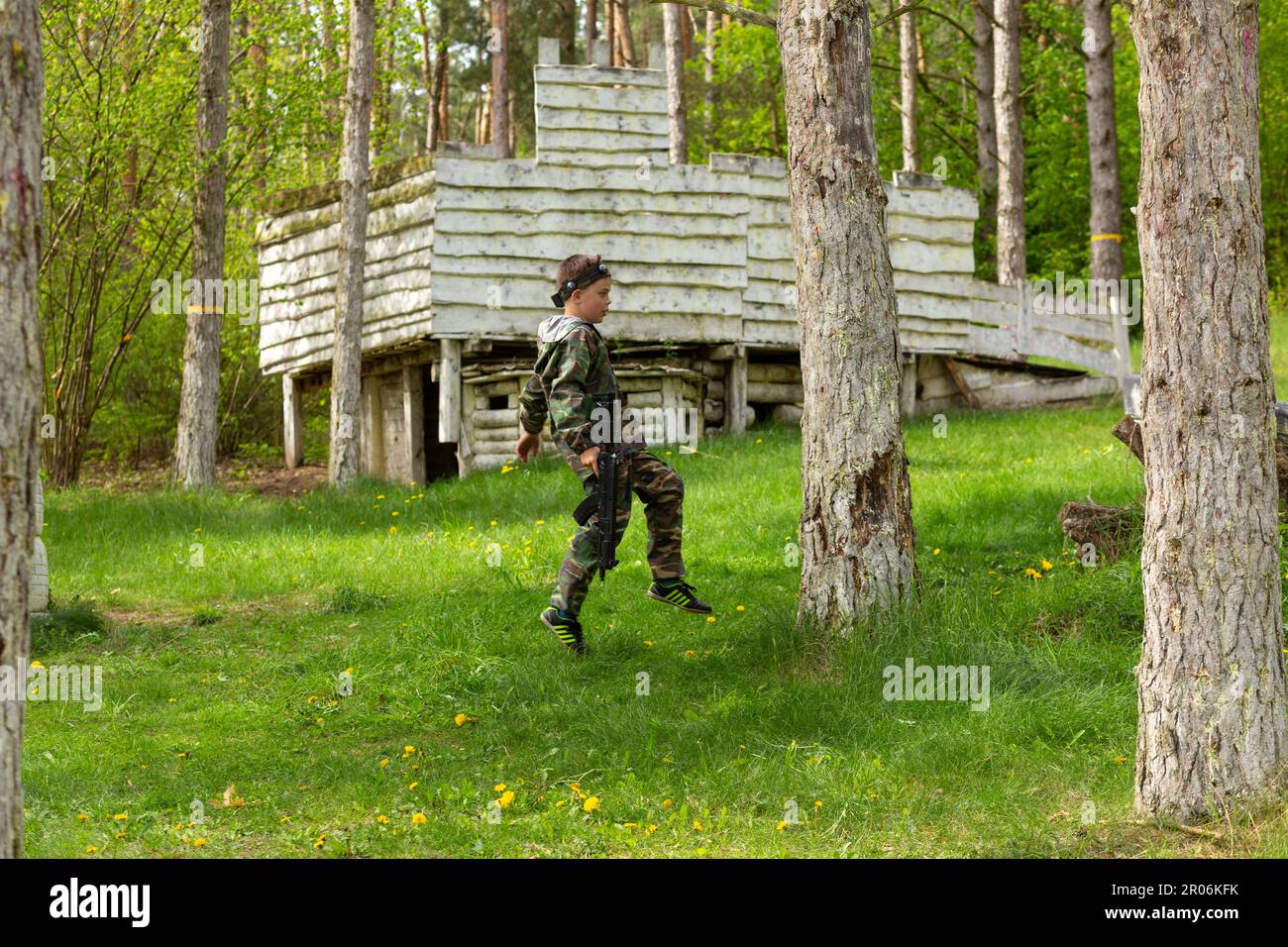 Boy weared in camouflage playing laser tag in special forest playground ...