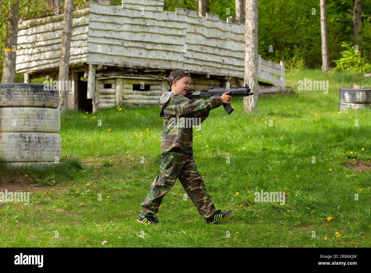 Boy weared in camouflage playing laser tag in special forest playground ...