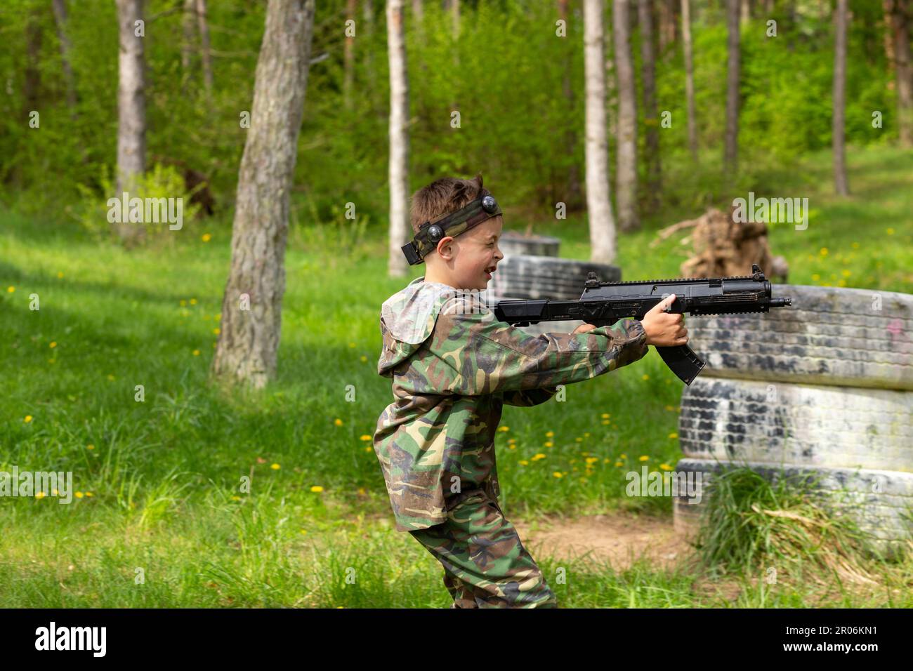 Boy weared in camouflage playing laser tag in special forest playground. Laser Tag is a command ...