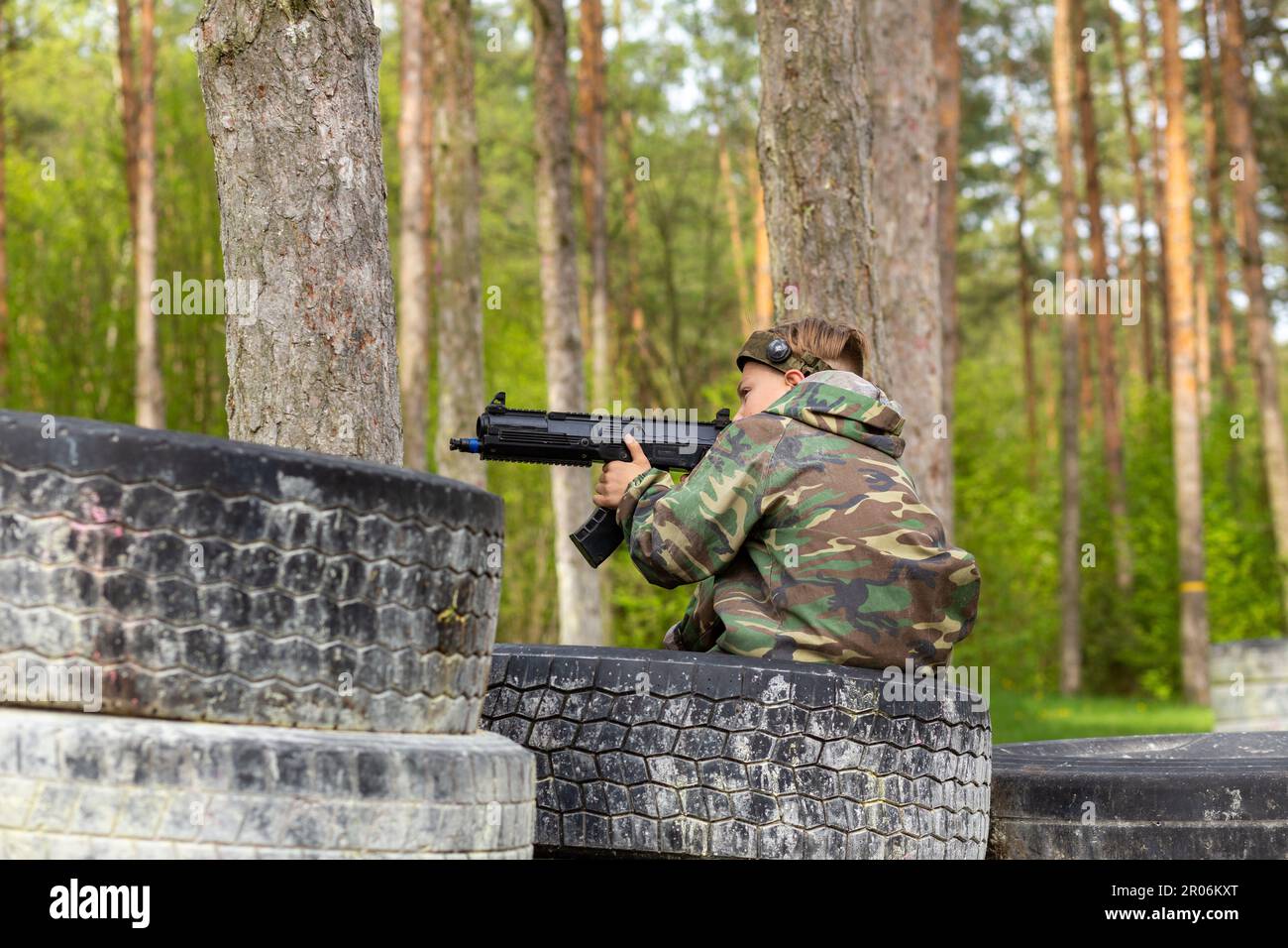 Boy weared in camouflage playing laser tag in special forest playground ...