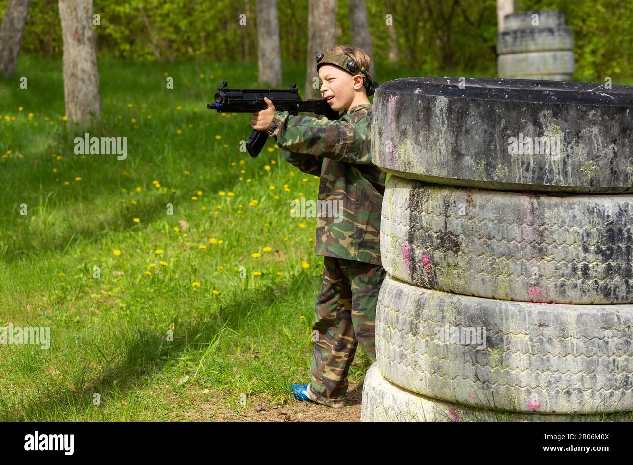 Boy weared in camouflage playing laser tag in special forest playground ...