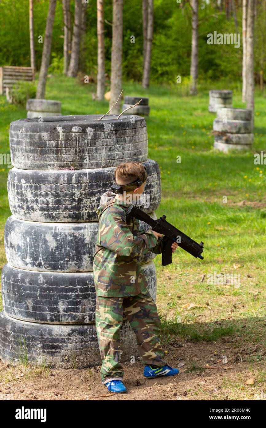 Boy weared in camouflage playing laser tag in special forest playground ...