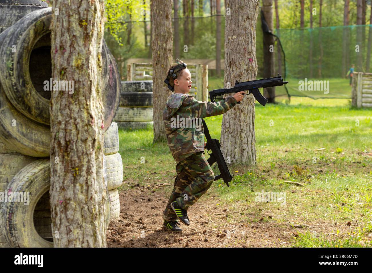 Boy weared in camouflage playing laser tag in special forest playground ...