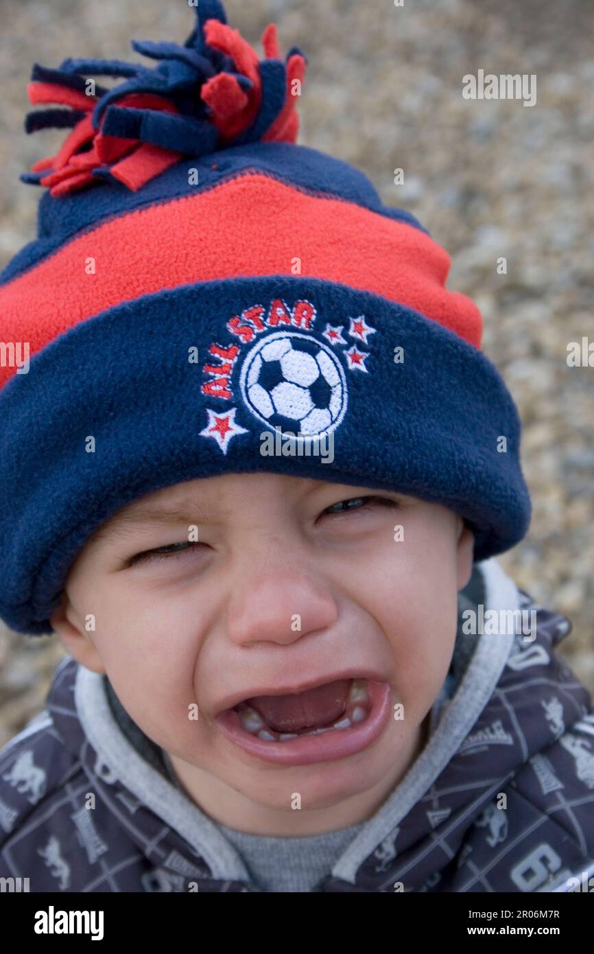 unhappy toddler in bobble hat throwing a tantrum Stock Photo - Alamy