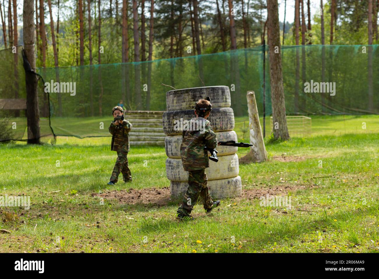Two boys weared in camouflage playing laser tag in special forest ...