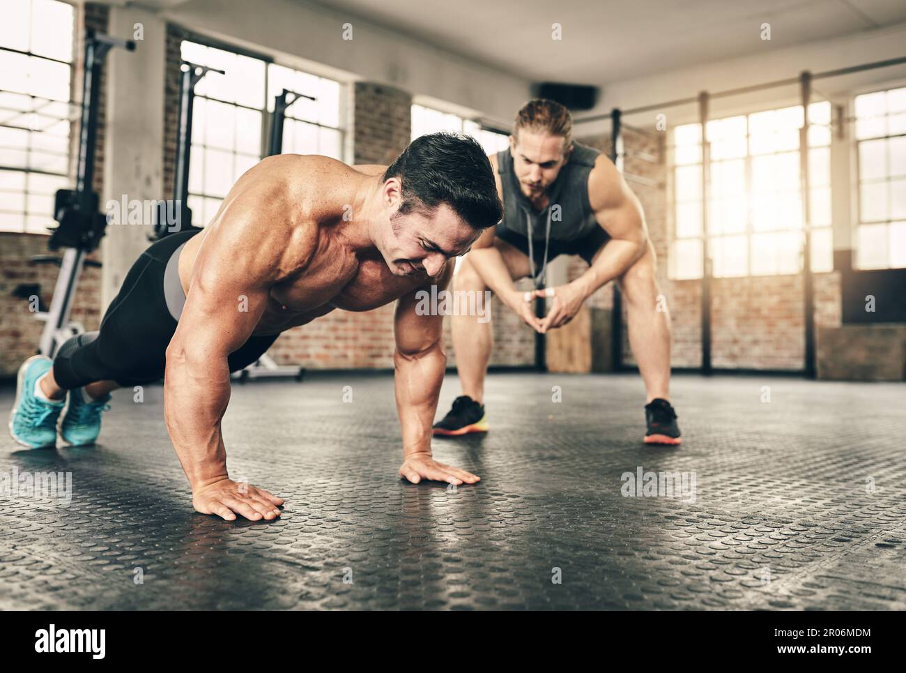 Just a few more. two fit and determined young men doing pushups one by one inside of a gym Stock ...