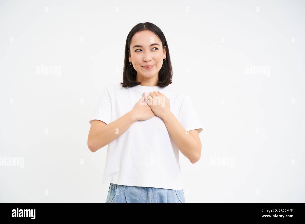 Portrait of asian woman with kind smile, holds hands on heart, concept ...