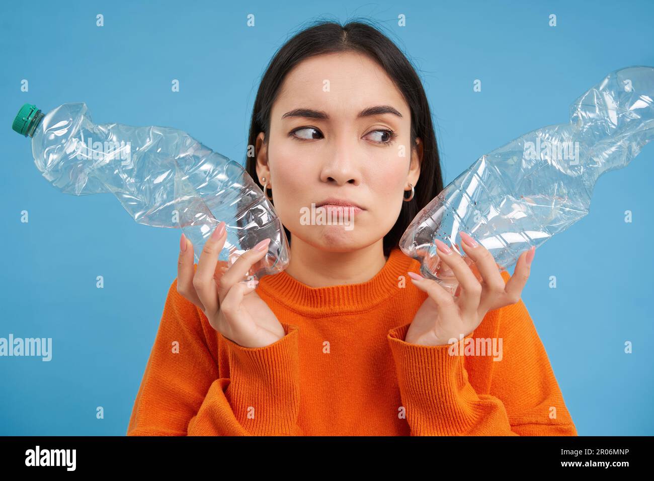 Thinking angry girl, shows two bottles, recycling plastic, goes green ...