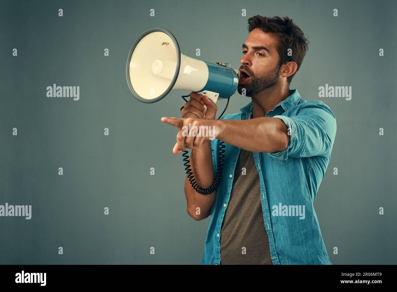 Listen up, everyone...Studio shot of a handsome young man talking into ...