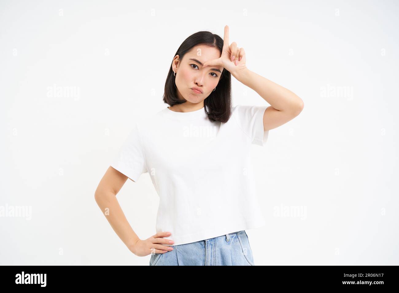 young woman shows L letter, loser gesture on forehead, mocking someone ...