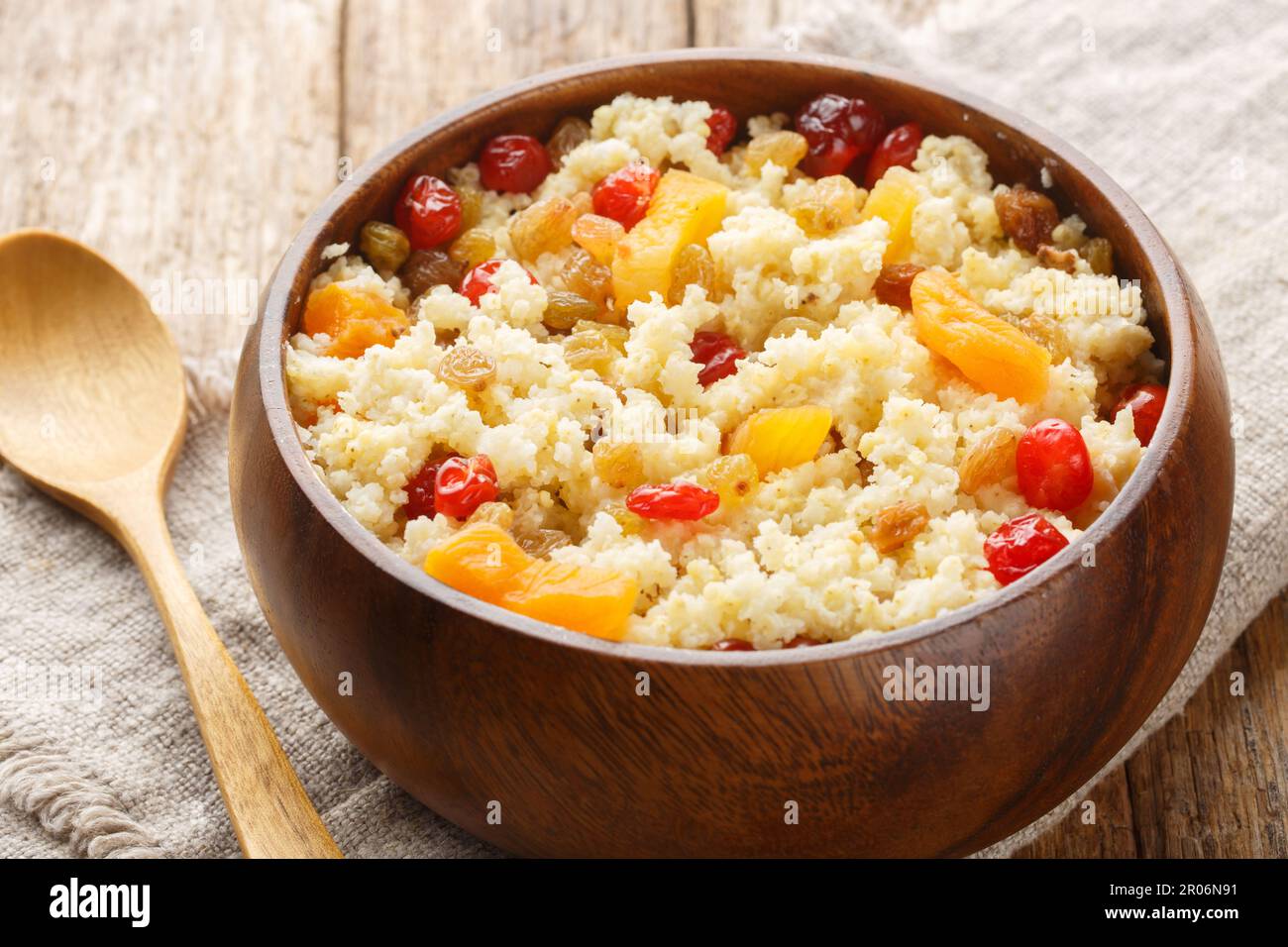 Homemade millet porridge with dried apricots, raisins and cherry close-up in a bowl on the table ...
