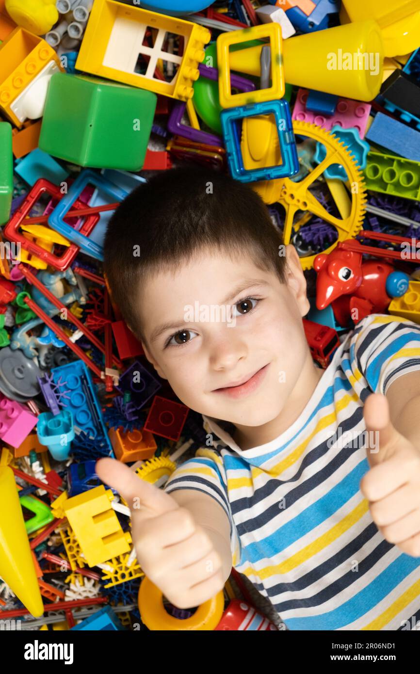 Happy 5 year old boy showing thumbs up lying among toys, top view Stock ...