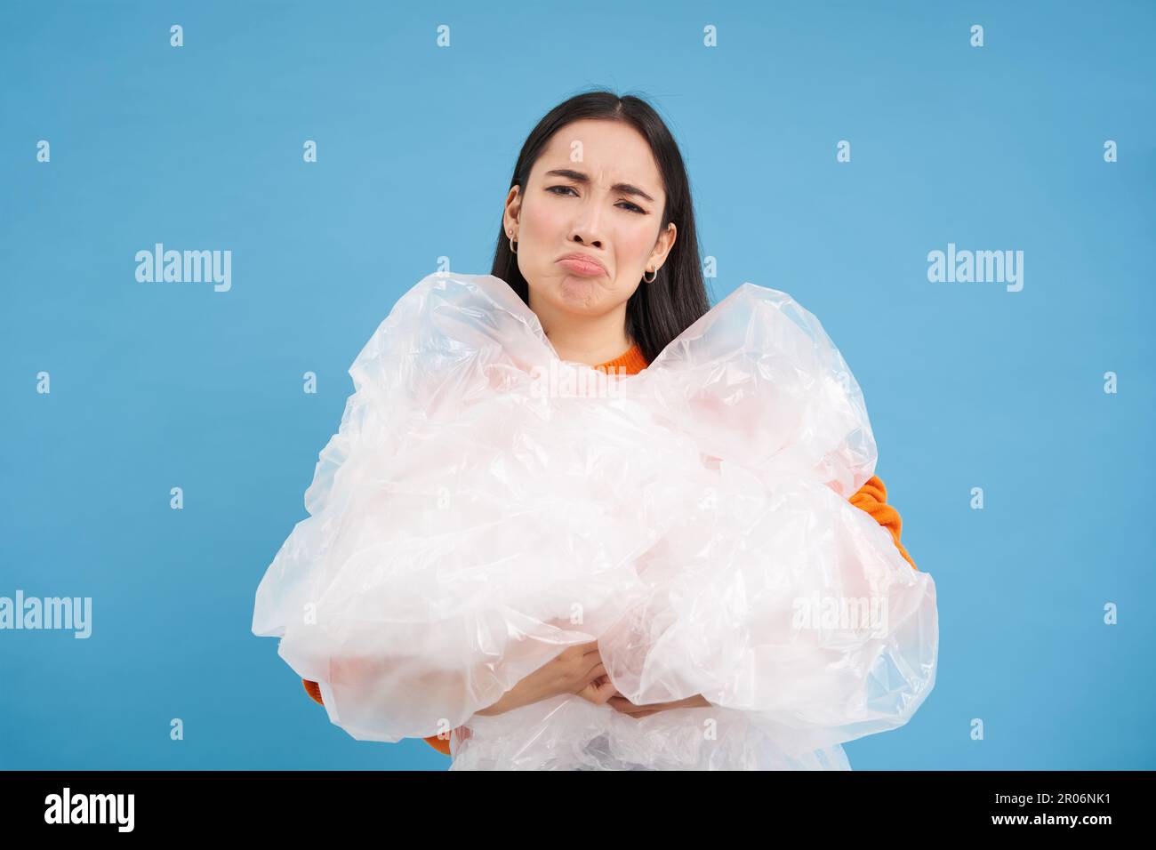 Annoyed woman holding loads of plastic in hands, looking bothered with ...