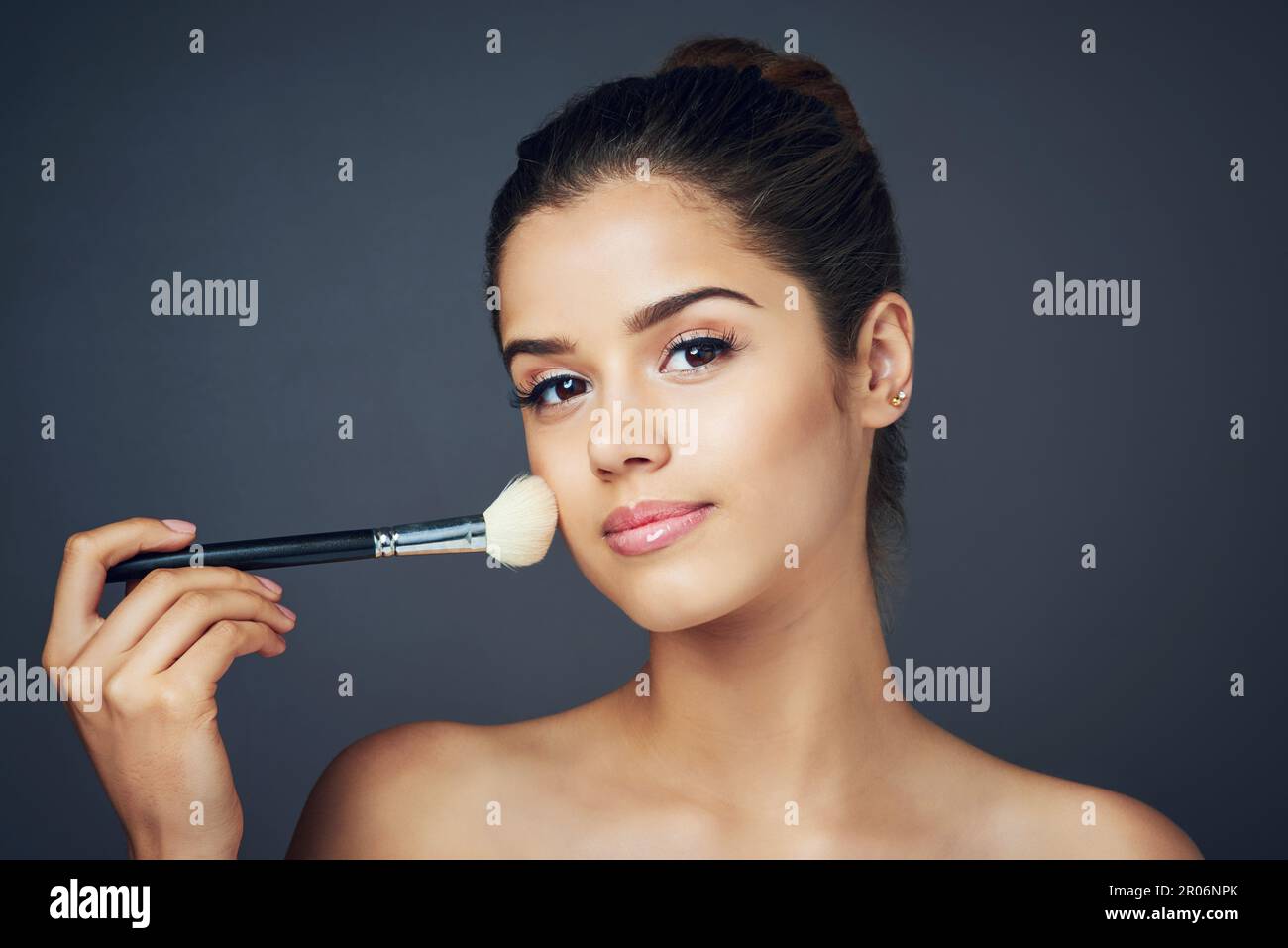 Adding some beauty by adding some blush. Studio shot of a beautiful young woman applying blush ...