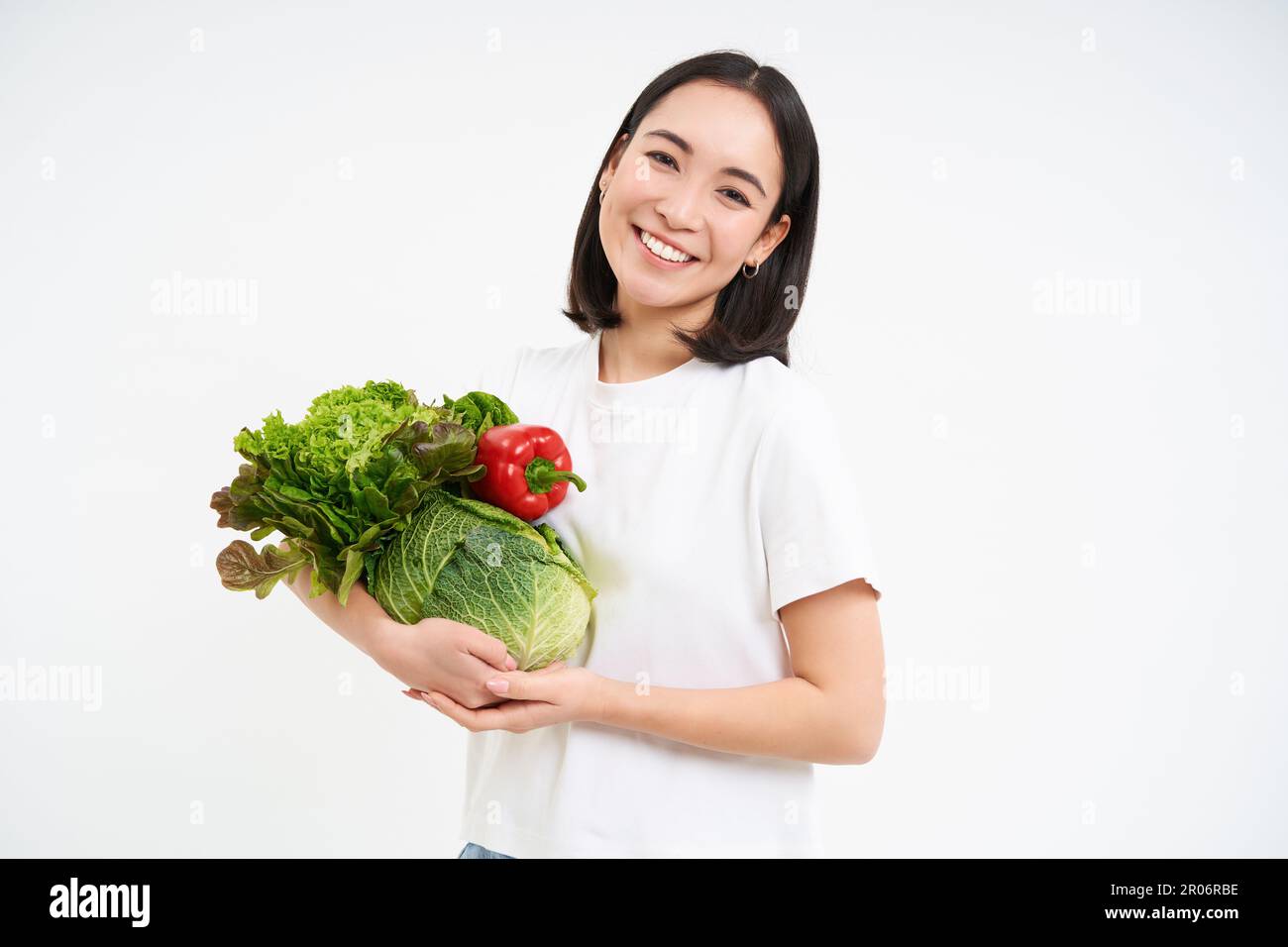 Smiling asian woman, showing her organic green vegetables, eating ...