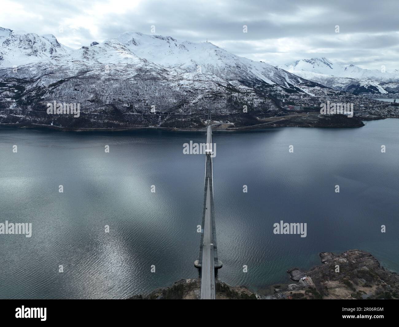 An aerial view of a a suspension bridge over water near snow-capped ...